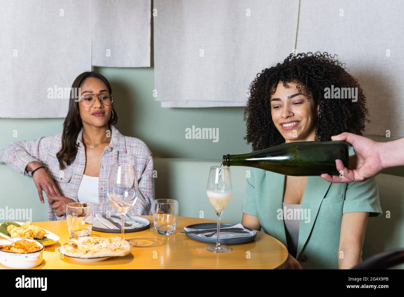 Male waiter serving drink in glass by businesswomen at restaurant Stock ...