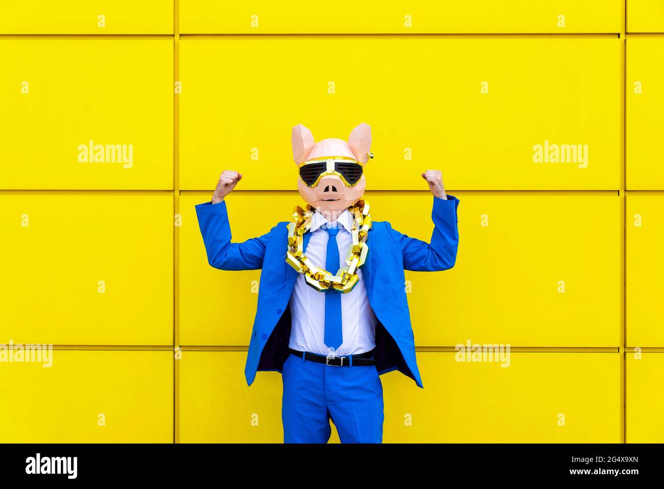Man wearing vibrant blue suit, pig mask and large golden chain flexing ...