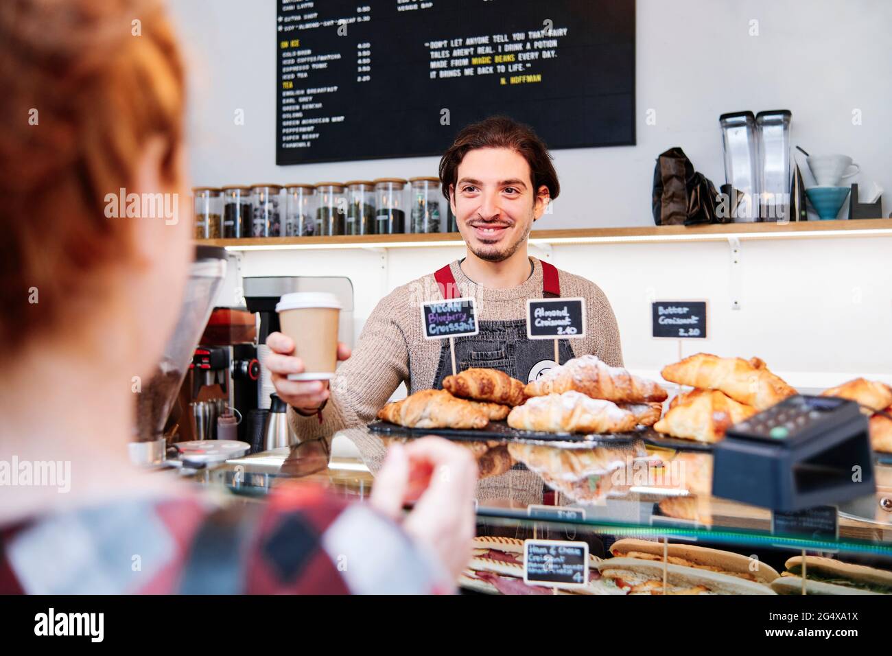 Smiling male owner offering coffee to female customer in cafe Stock ...