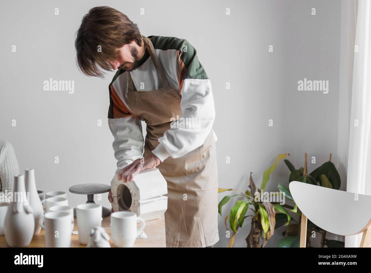 Male artisan checking ceramic model while standing at workplace Stock ...