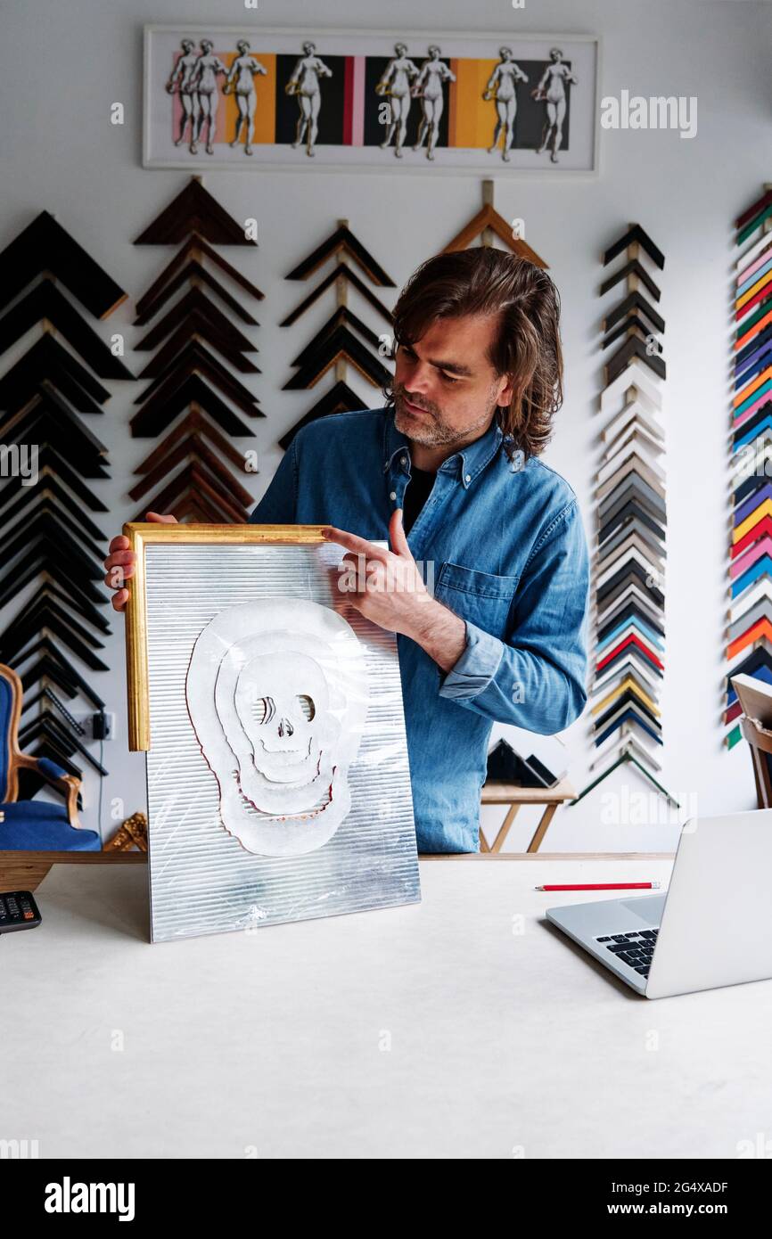 Craftsman adjusting border on picture frame while working in shop Stock ...