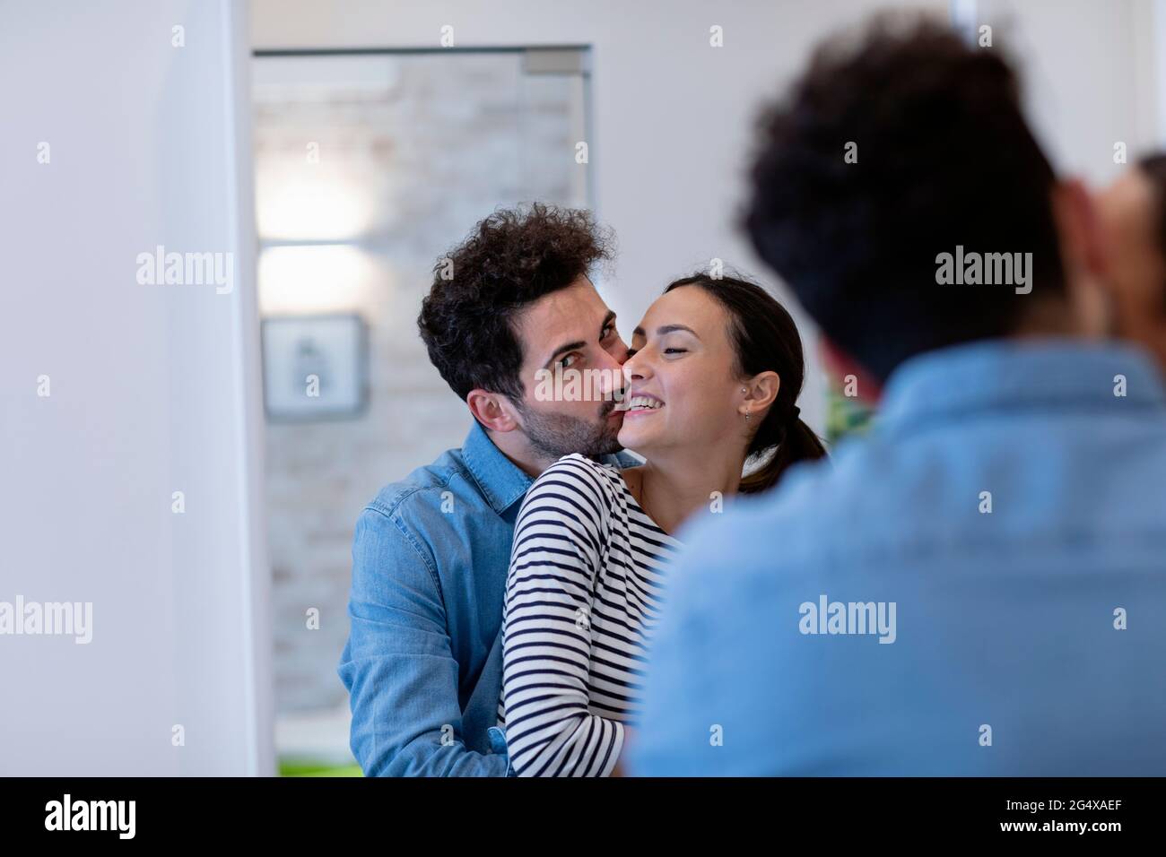 Boyfriend kissing girlfriend on cheek in front of mirror at home Stock ...