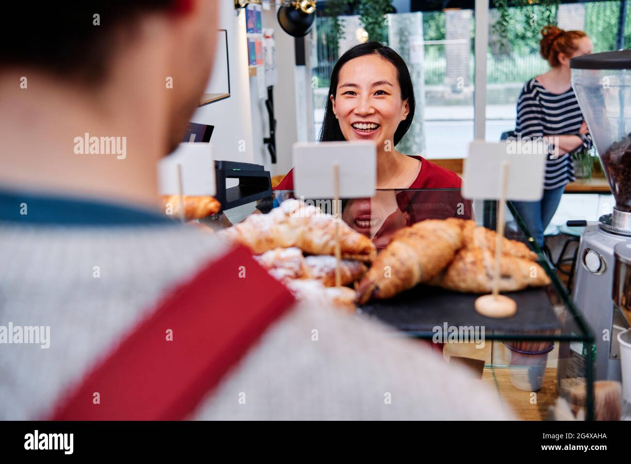 Smiling female customer talking with male owner at counter with female ...