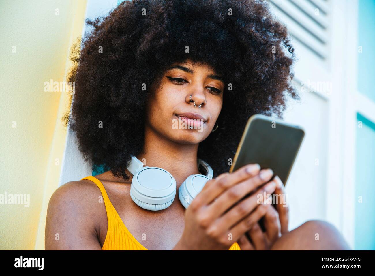 Young Afro woman text messaging through mobile phone Stock Photo - Alamy