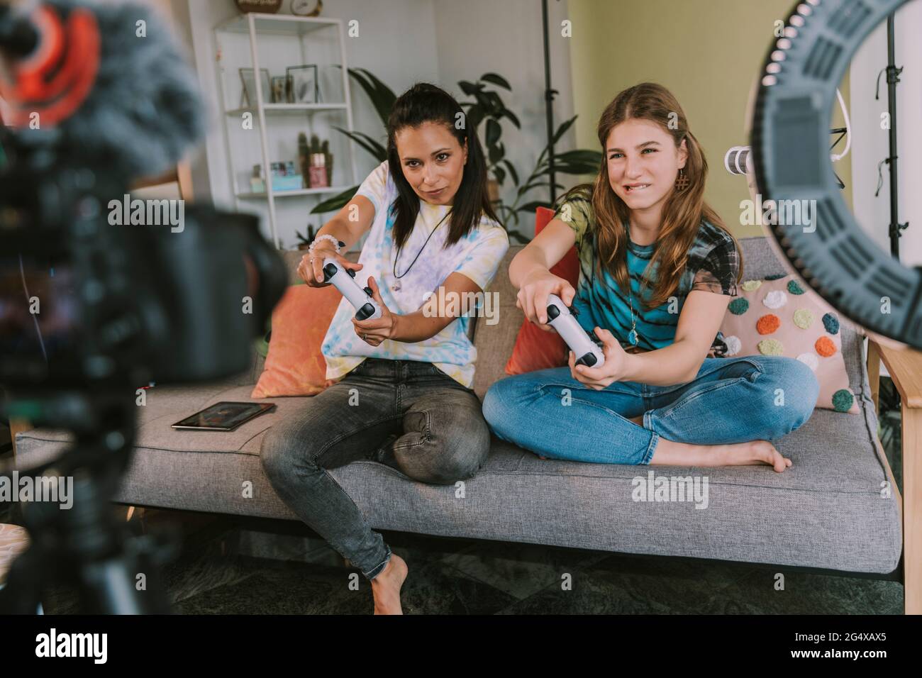 Concentrated female gamers playing video game while vlogging at home ...