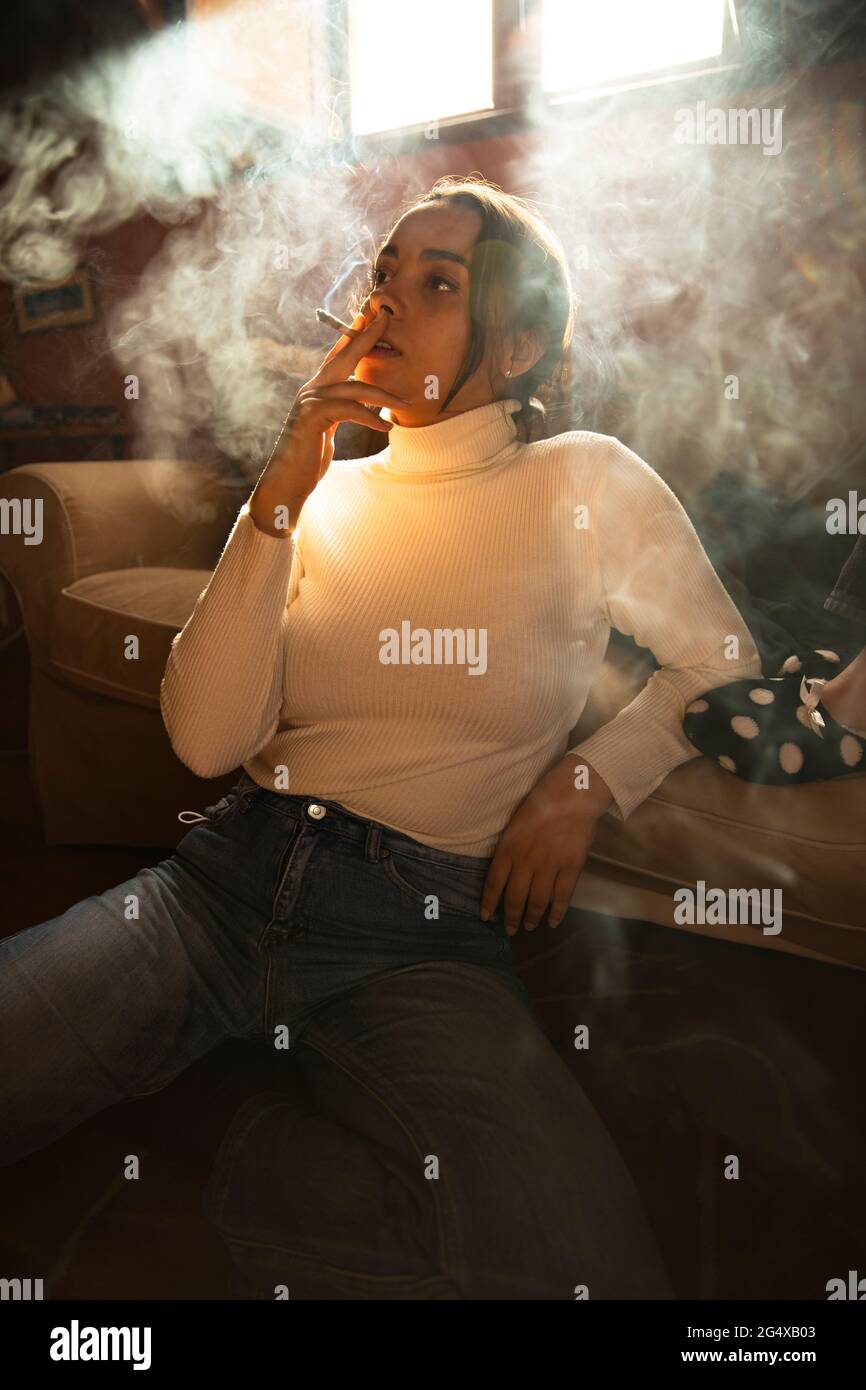 Thoughtful woman looking away while smoking cigarette at home Stock ...