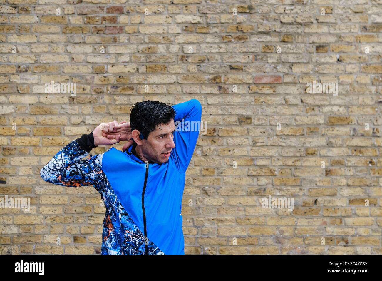 Mature man stretching hands while standing in front of brick wall Stock ...