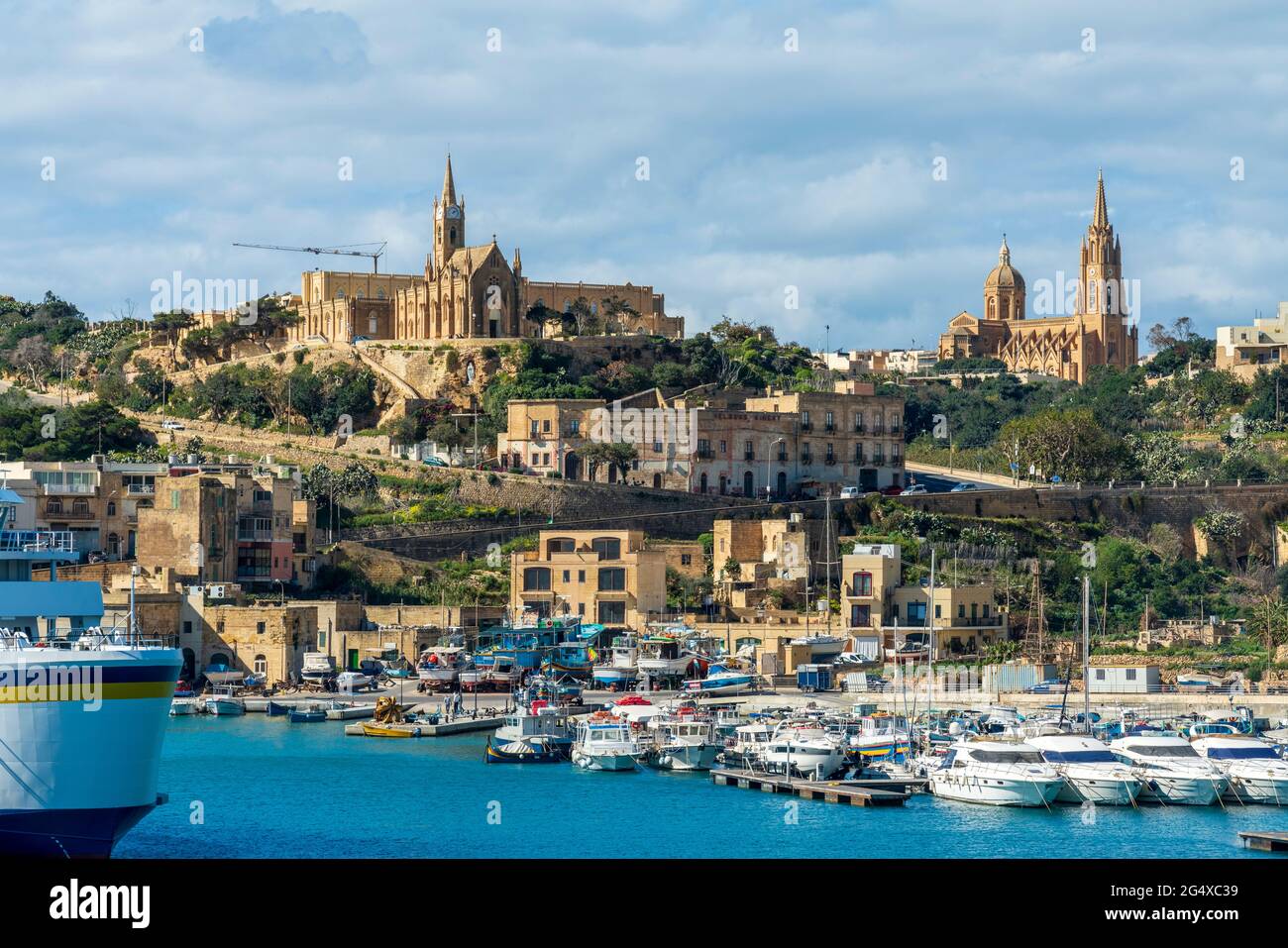 Yachts moored in sea by ghajnsielem parish church in city on sunny day ...