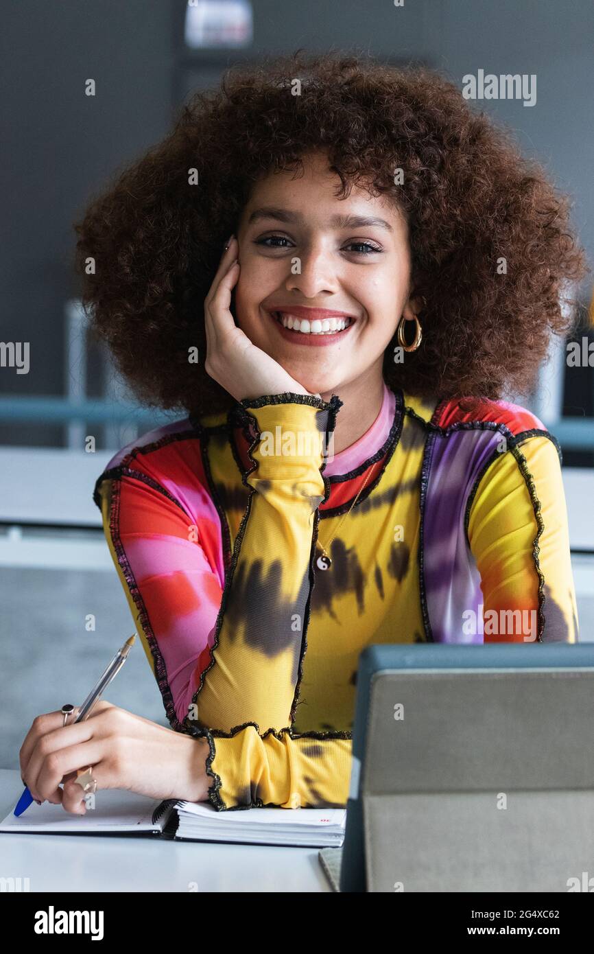 Female university student with hand on chin smiling in library Stock ...