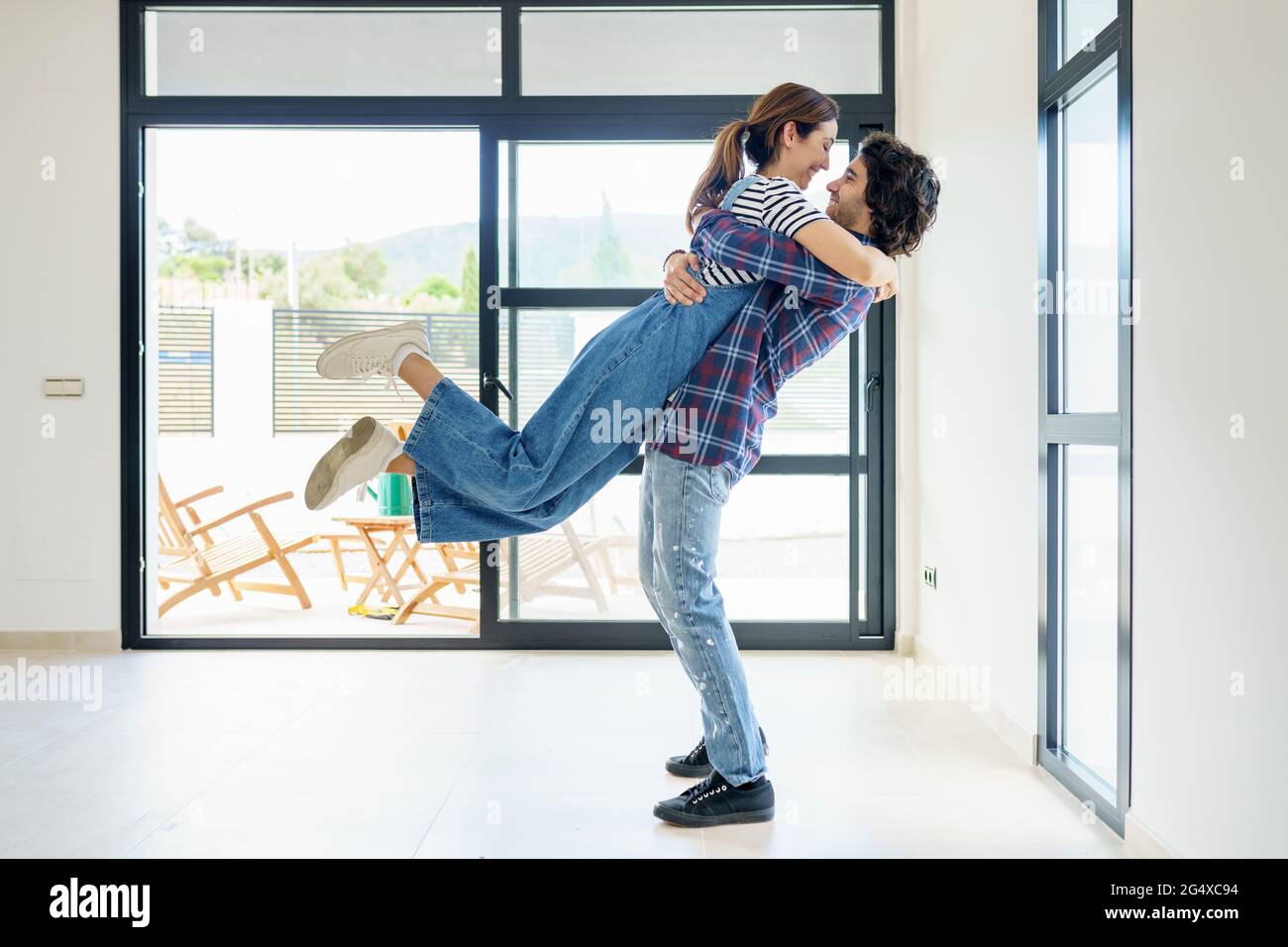 Cheerful boyfriend carrying girlfriend while standing in new home Stock ...