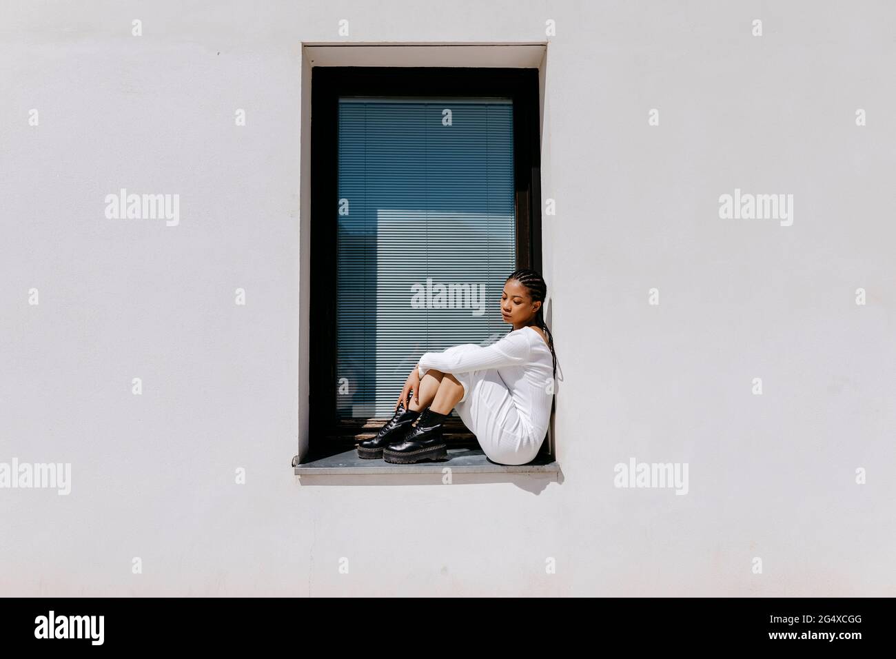 Young woman sitting on window sill Stock Photo - Alamy