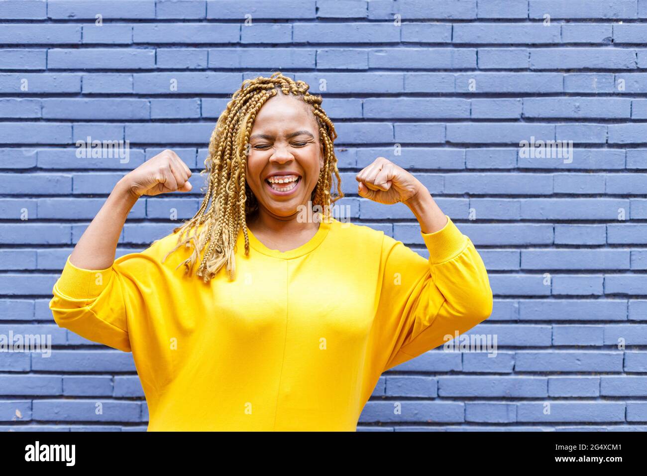 Cheerful plus size woman with eyes closed flexing muscles in front of ...