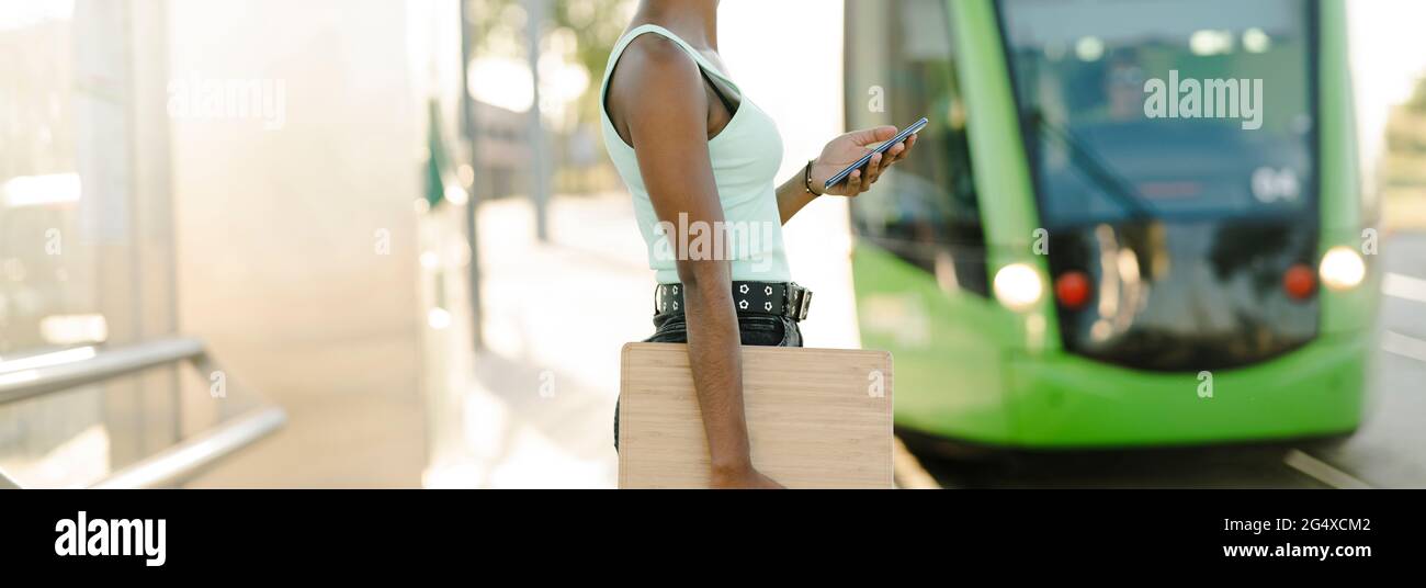 Woman holding smart phone while tram arriving at tram station Stock ...