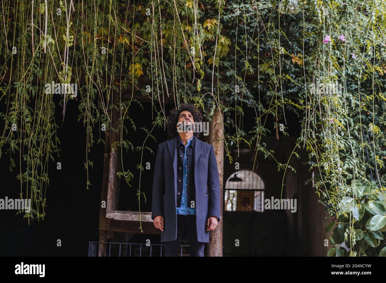 Thoughtful man looking up while standing in front of building Stock ...