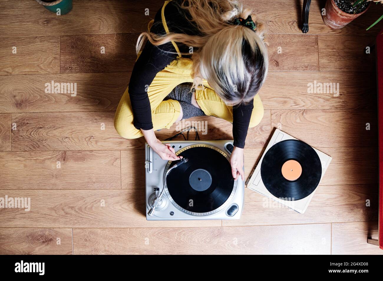 Woman using turntable while sitting on floor Stock Photo - Alamy