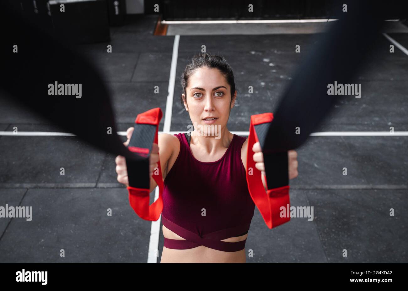 Mid adult female athlete pulling resistance band while exercising in ...
