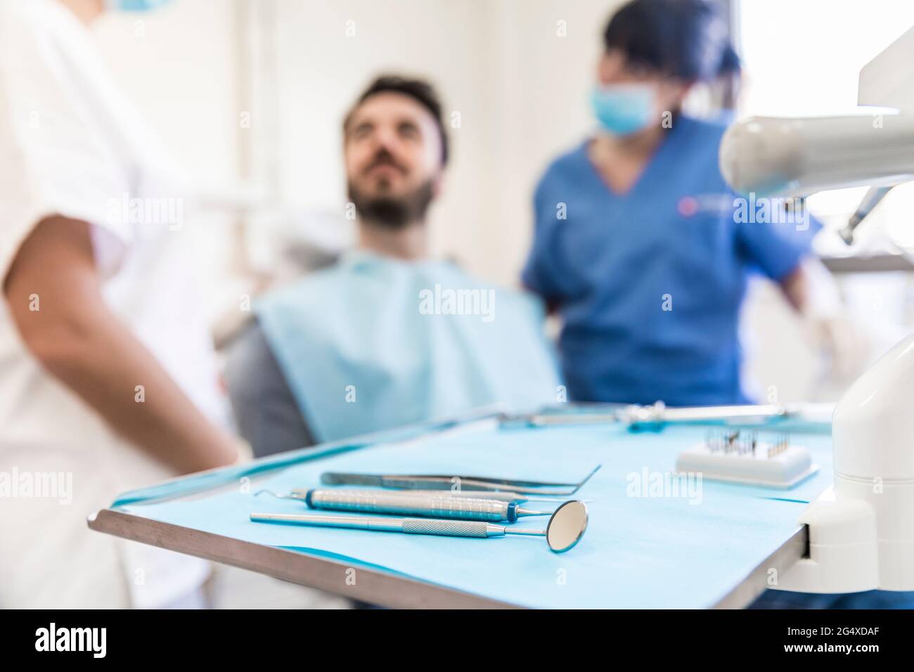 Dental equipments on tray with female dentists and male patient in ...