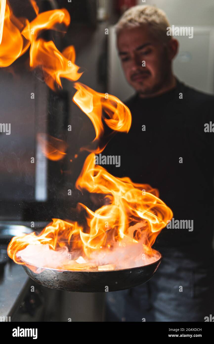 Chef holding flaming pan in kitchen Stock Photo - Alamy