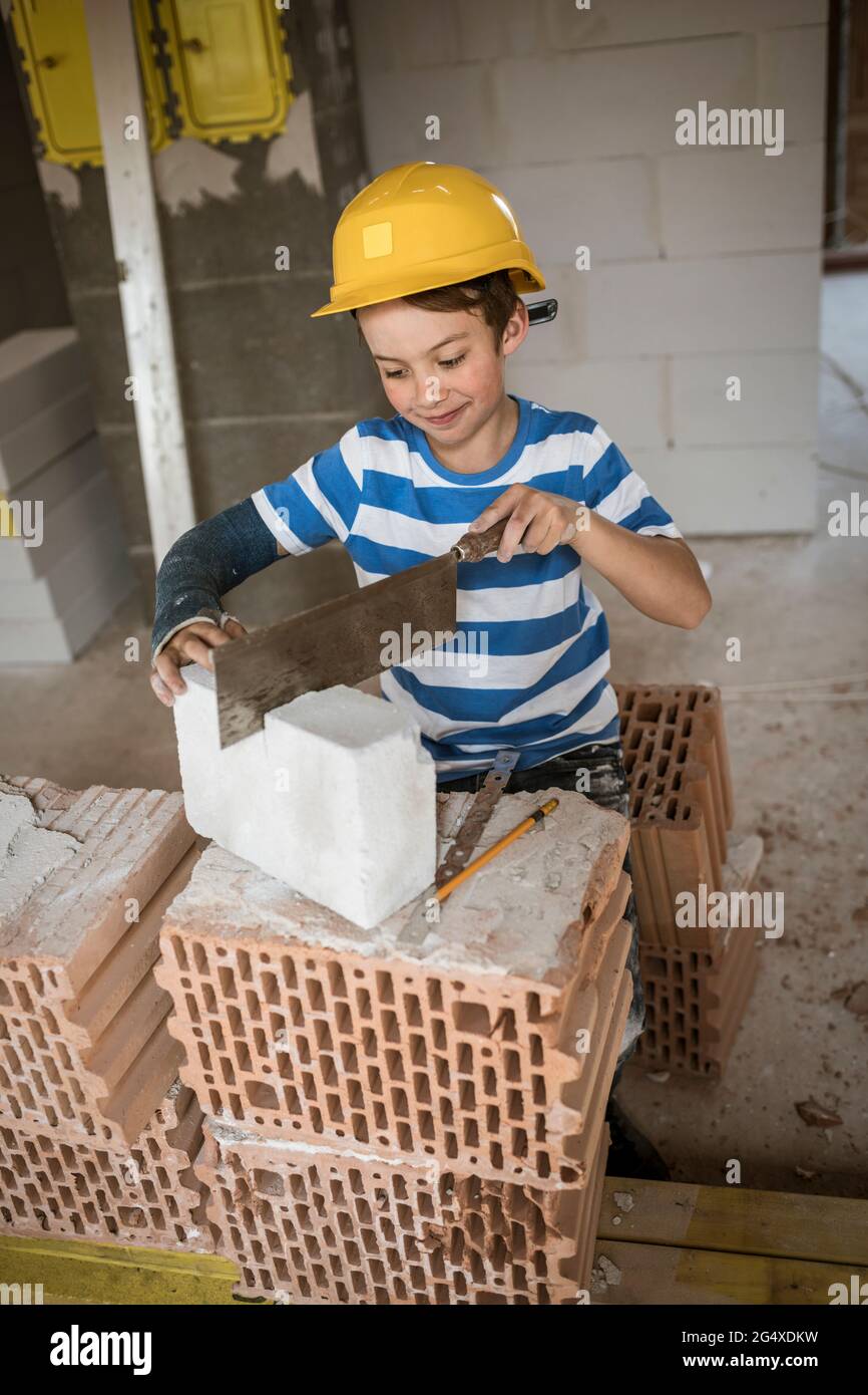 Boy with broken arm cutting block during rebuilding house Stock Photo ...