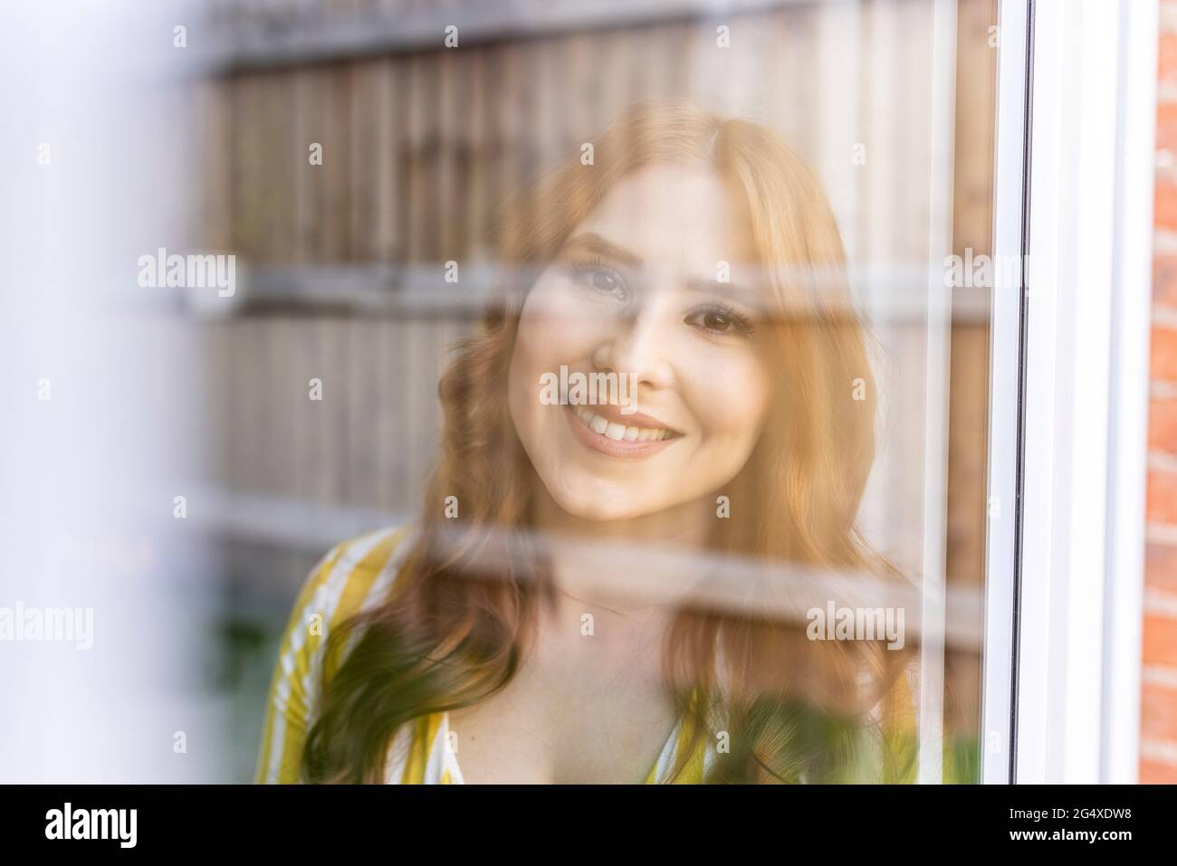 Beautiful smiling redhead woman seen through window Stock Photo - Alamy