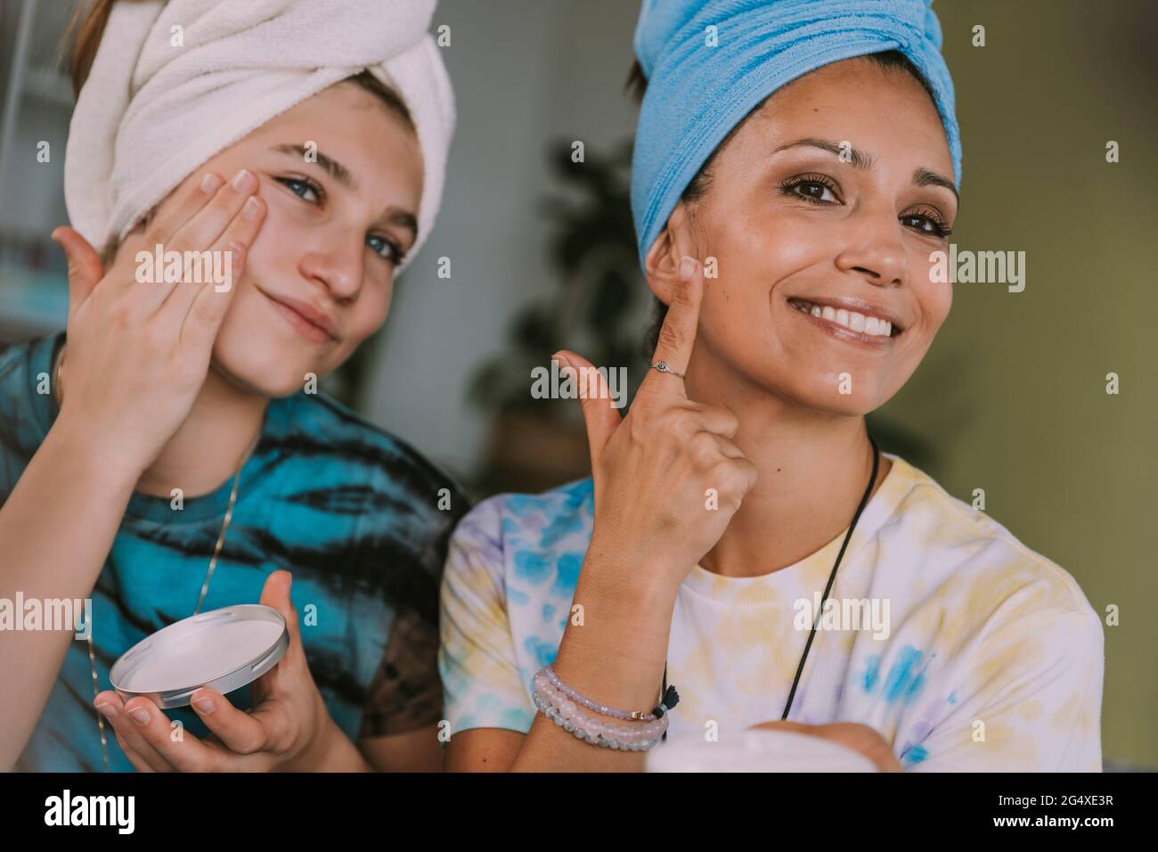 Beautiful female influencers applying face cream while vlogging at home ...