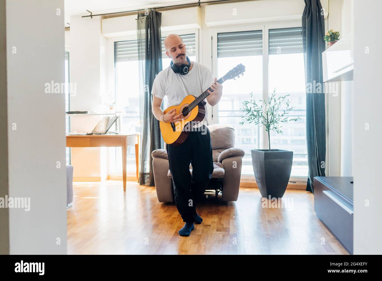 Young male guitarist playing in front of reclining chair at home Stock ...