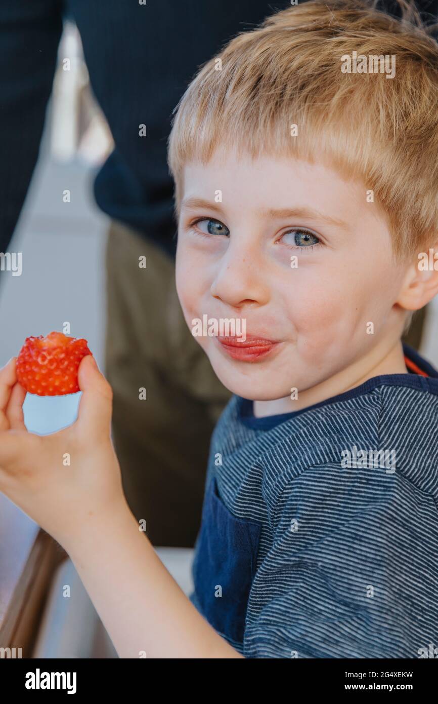 Cute boy eating strawberry at home Stock Photo - Alamy