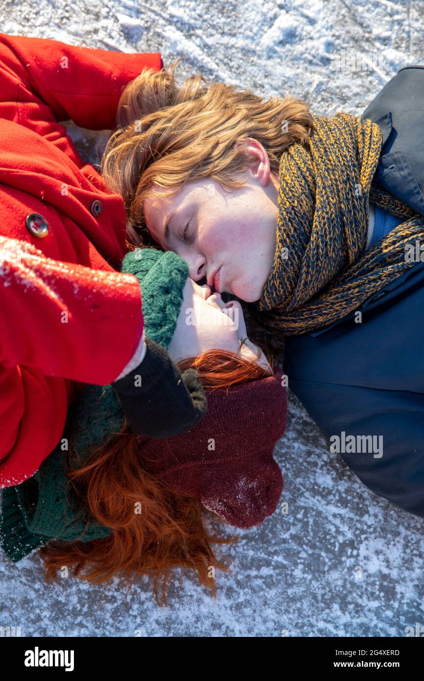 Couple kissing while lying on ice Stock Photo - Alamy