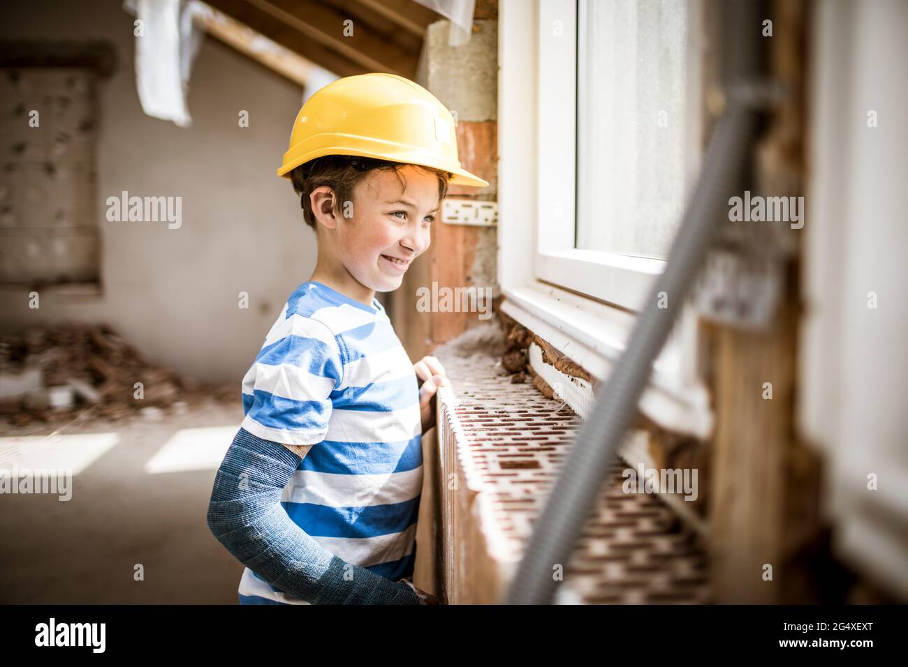 Boy wearing hardhat looking through window at construction site Stock ...