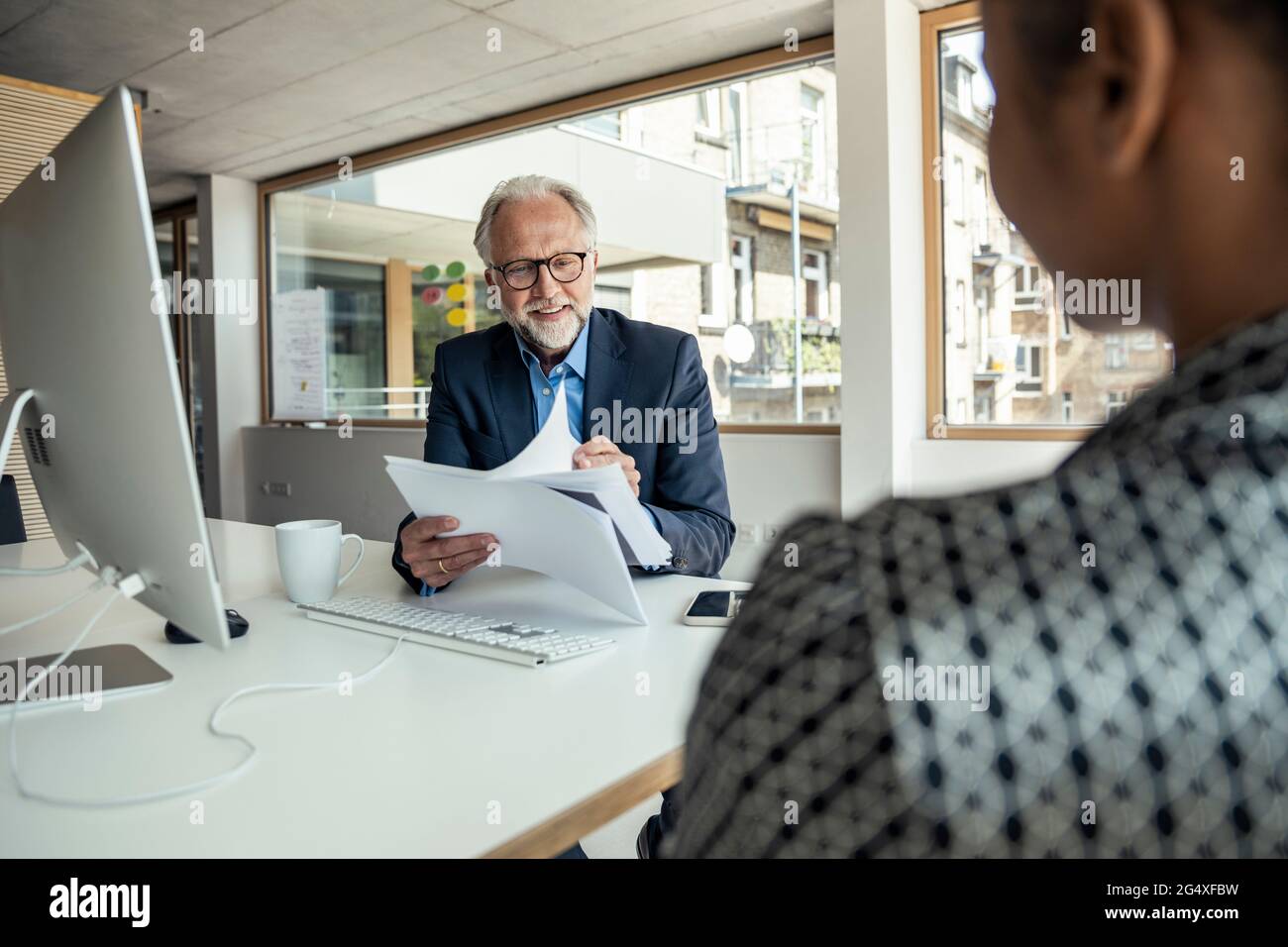 Smiling male professional reading documents in front of computer at ...
