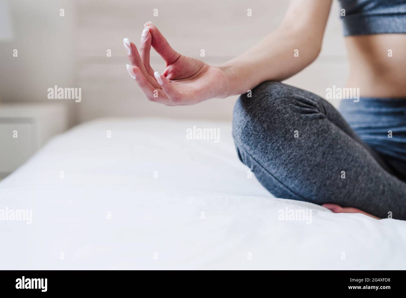 Young woman in lotus position sitting on bed at home Stock Photo - Alamy