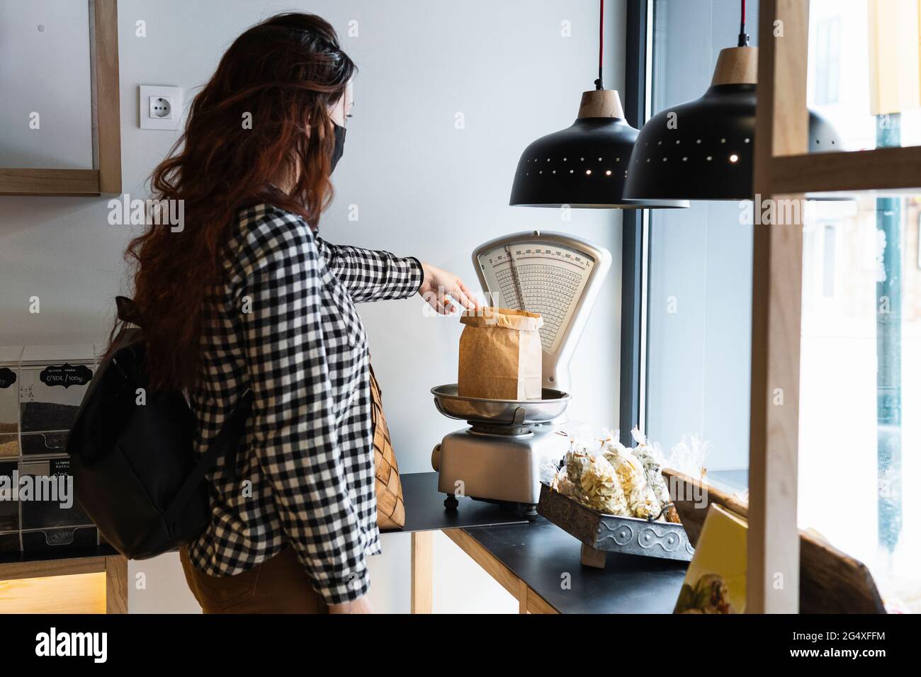 Woman with backpack measuring food on weight scale at store during ...