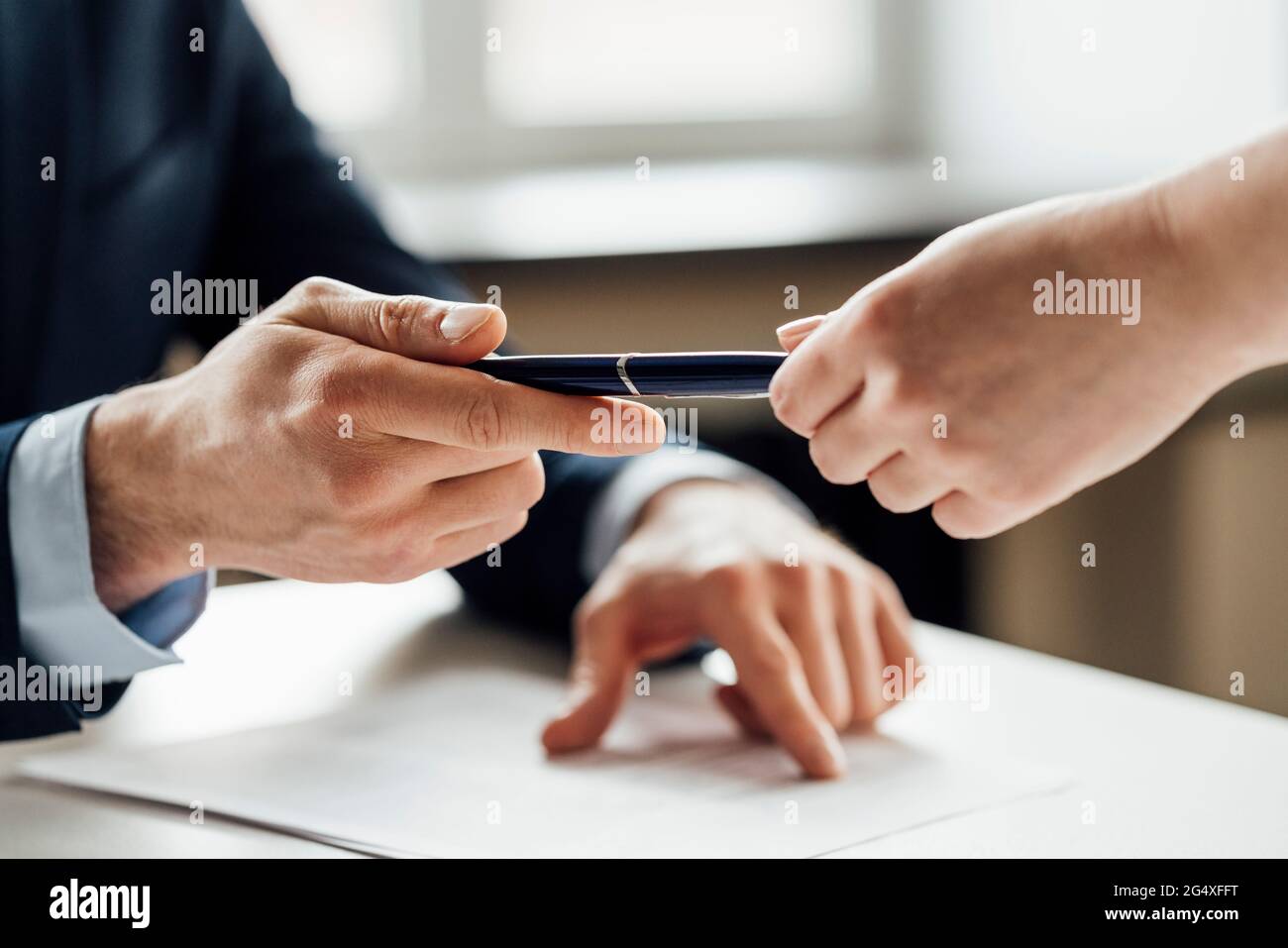 Male entrepreneur giving pen to colleague in office Stock Photo - Alamy