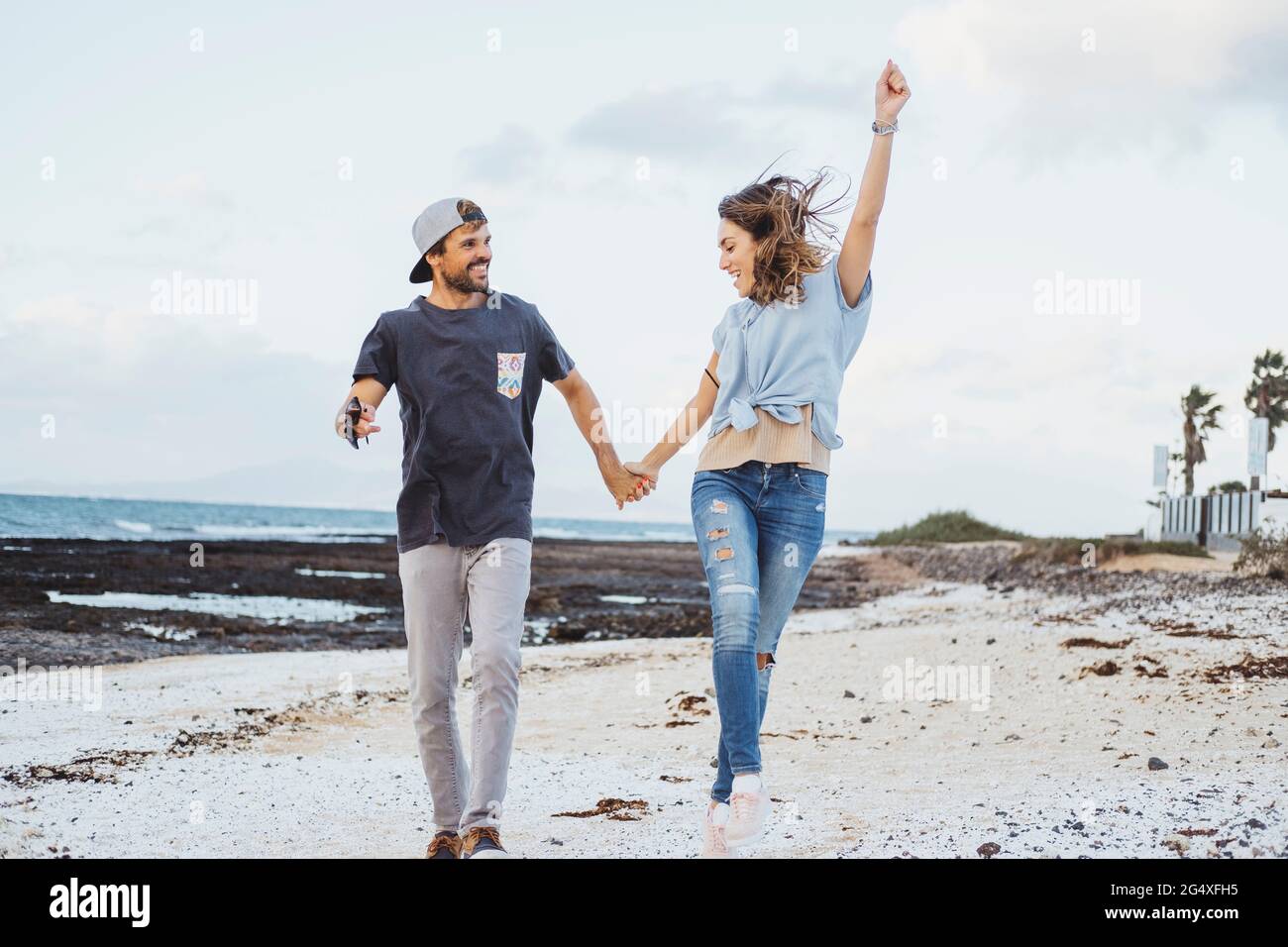 Happy girlfriend holding hand of boyfriend while running at beach Stock ...