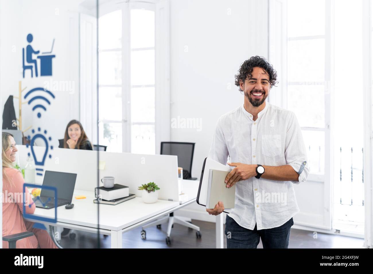 Smiling male entrepreneur walking out of office cubicle after meeting ...