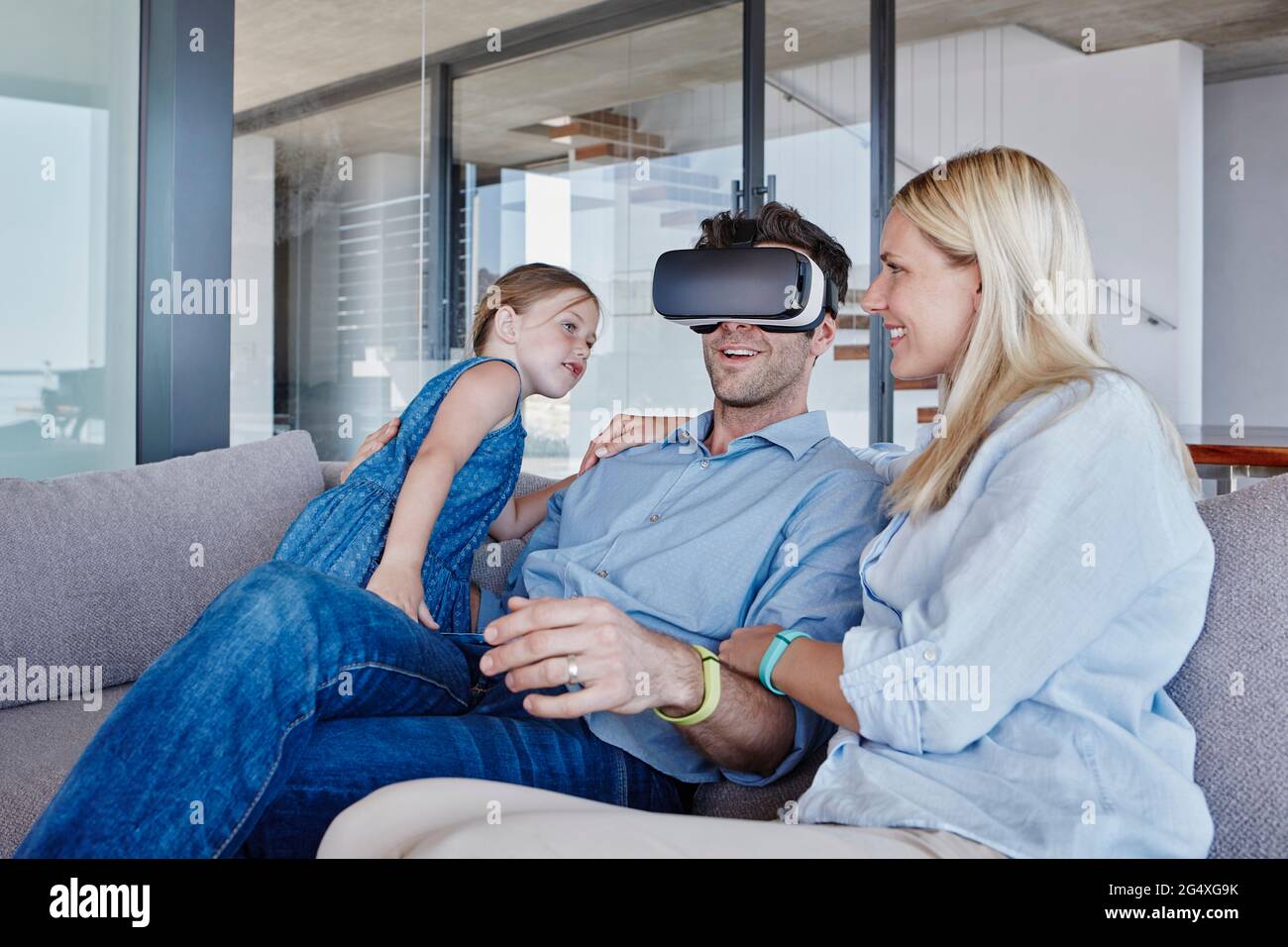 Smiling man wearing virtual reality simulator sitting by woman and ...
