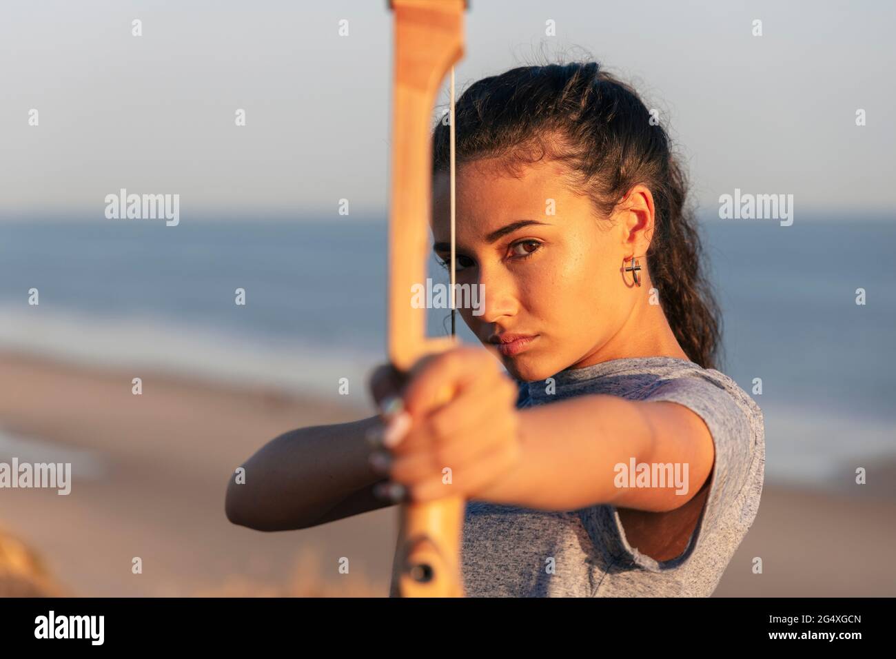 Serious woman practicing archery at beach Stock Photo - Alamy