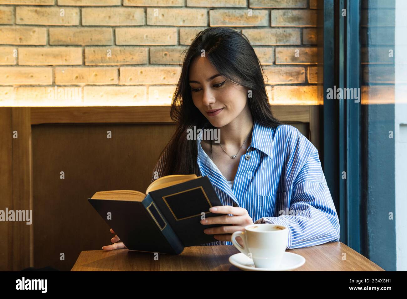Beautiful woman reading book while having coffee at bar Stock Photo - Alamy