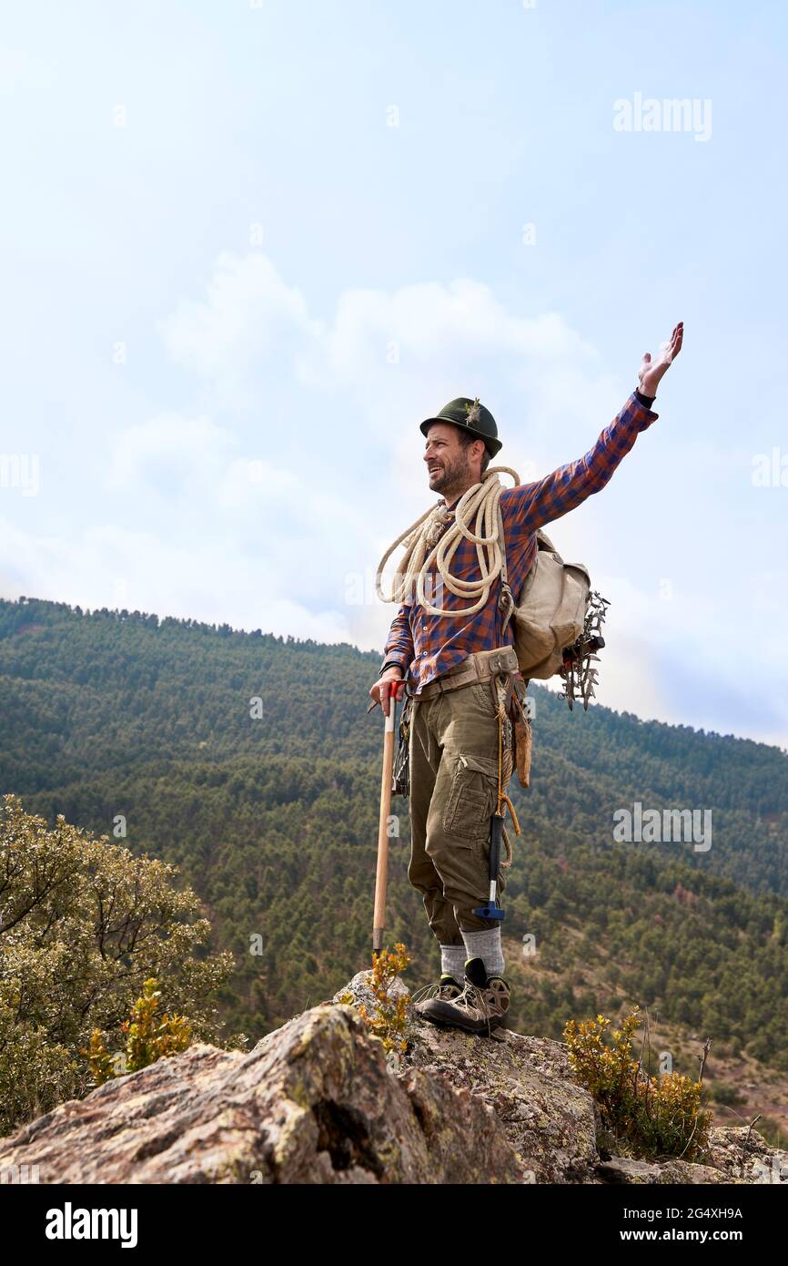Male mountaineer standing with hand raised on mountain Stock Photo - Alamy