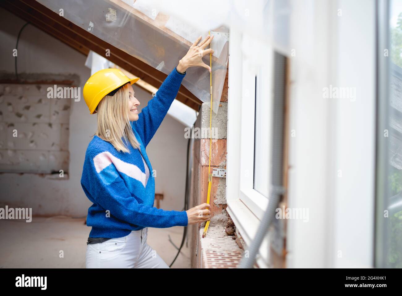 Female building contractor measuring with folding ruler at construction ...