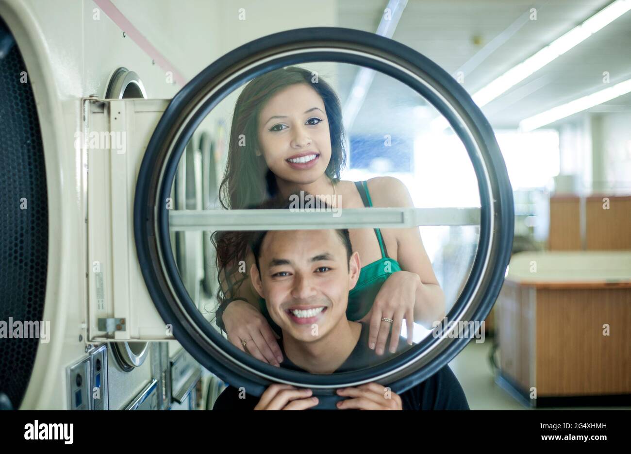 Smiling man with woman having fun at laundromat Stock Photo - Alamy