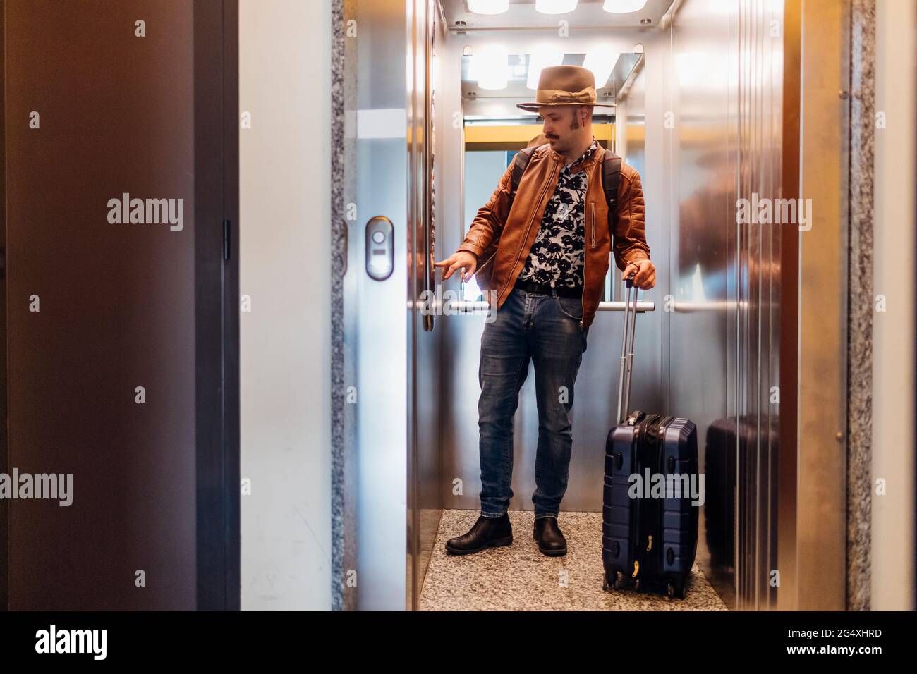 Man in hat pushing button in elevator Stock Photo - Alamy