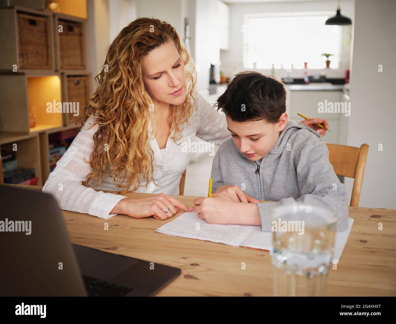 Mother teaching while son writing at home Stock Photo - Alamy