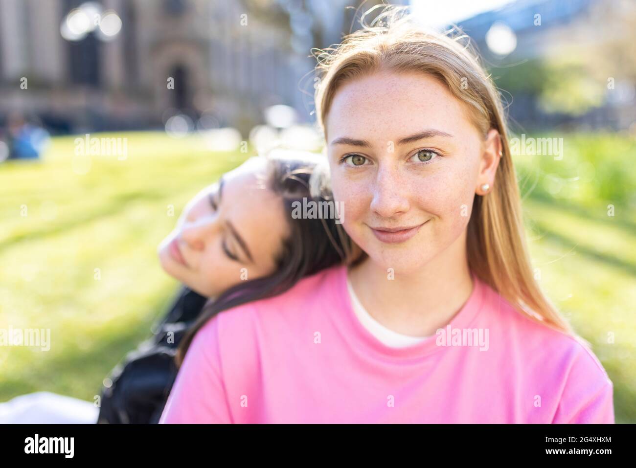 Beautiful blond woman with head on shoulder of female friend in public ...