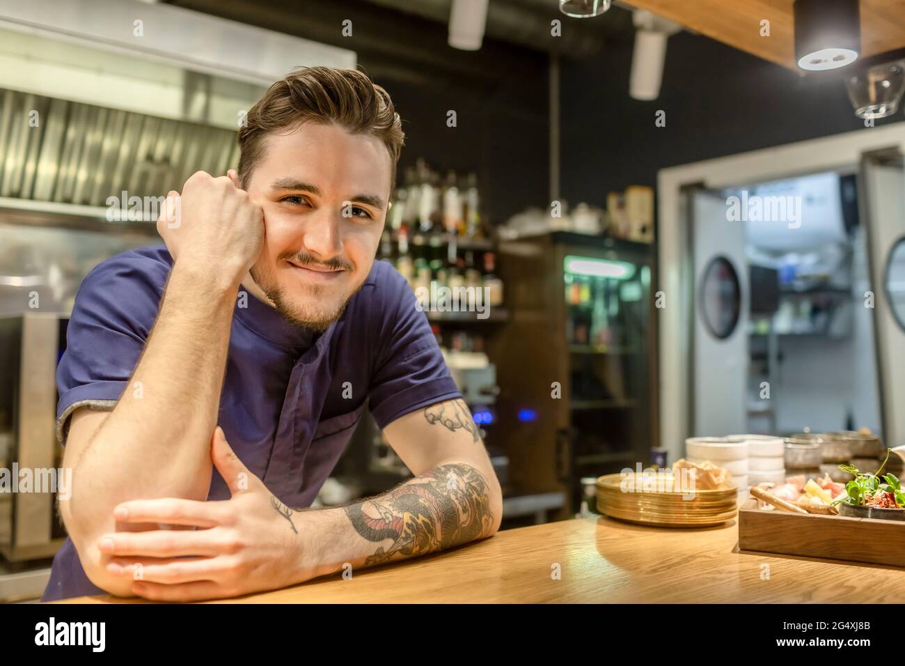 Smiling male bartender standing while leaning on bar counter Stock ...