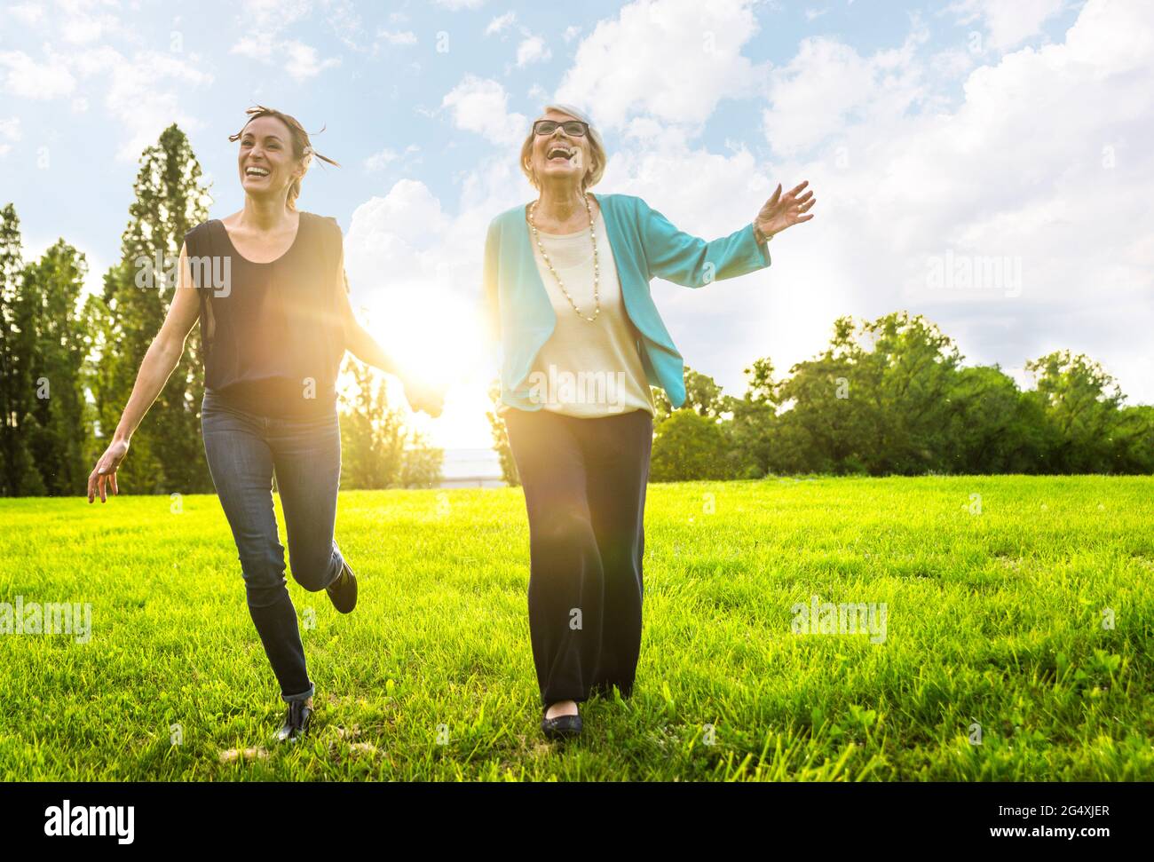 Happy women holding hands while running on meadow Stock Photo - Alamy