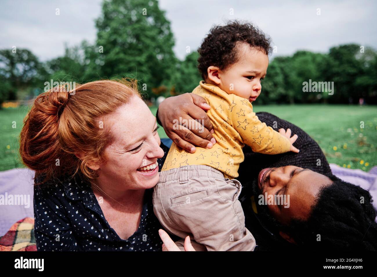 Multi-ethnic family enjoying with son at park Stock Photo - Alamy