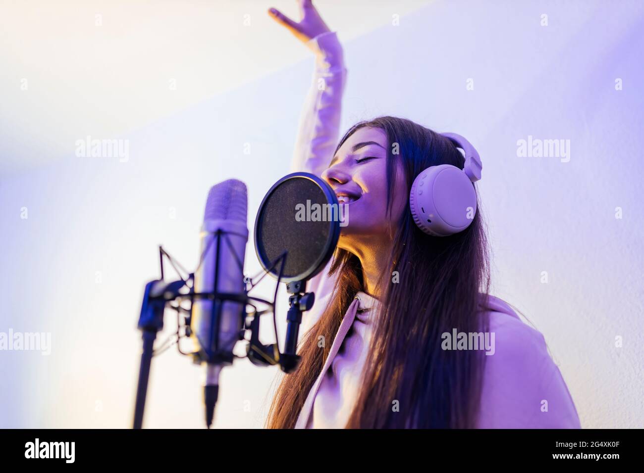 Female singer with hand raised singing at studio Stock Photo - Alamy