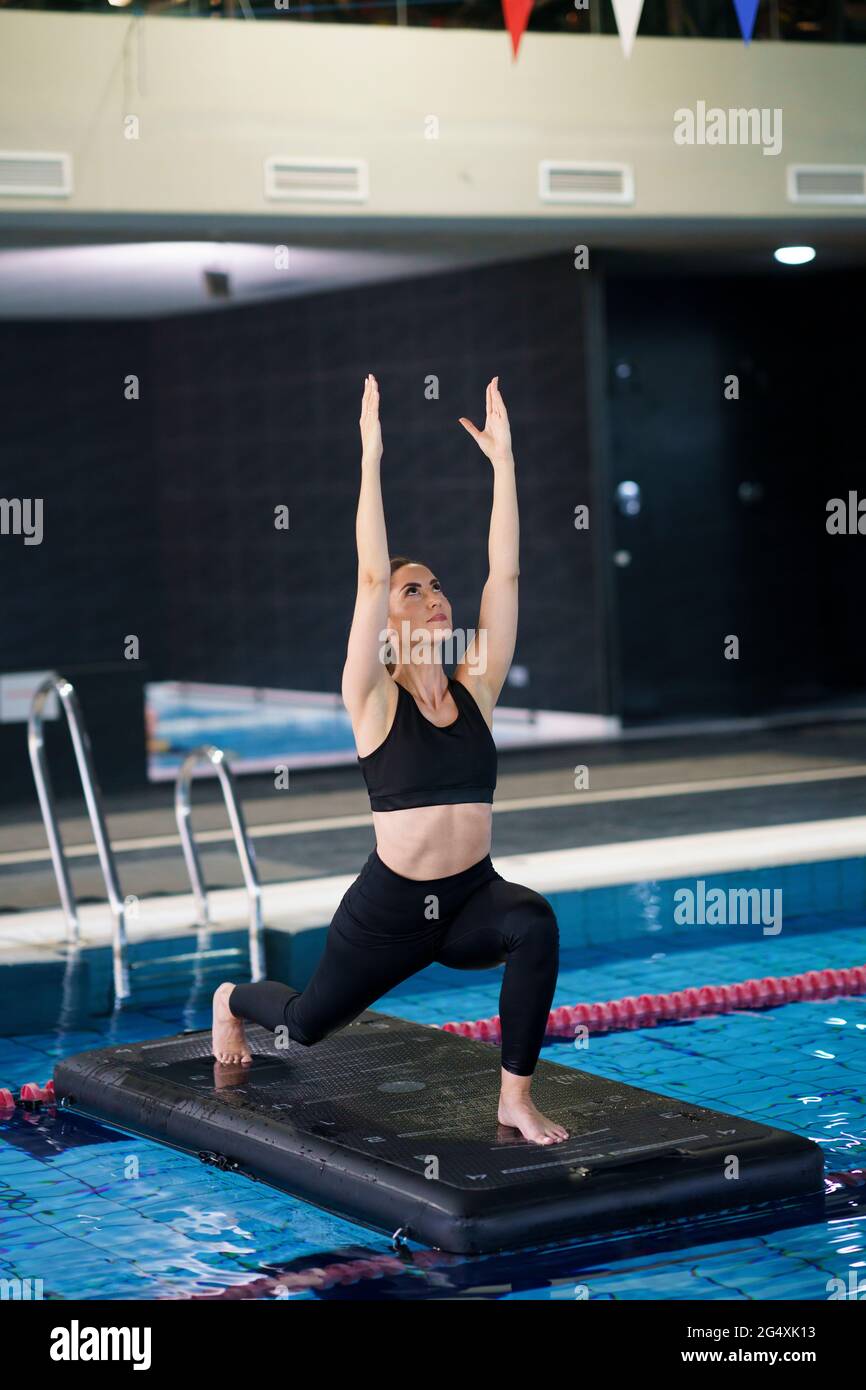 Woman practicing Warrior pose I on raft in swimming pool Stock Photo ...