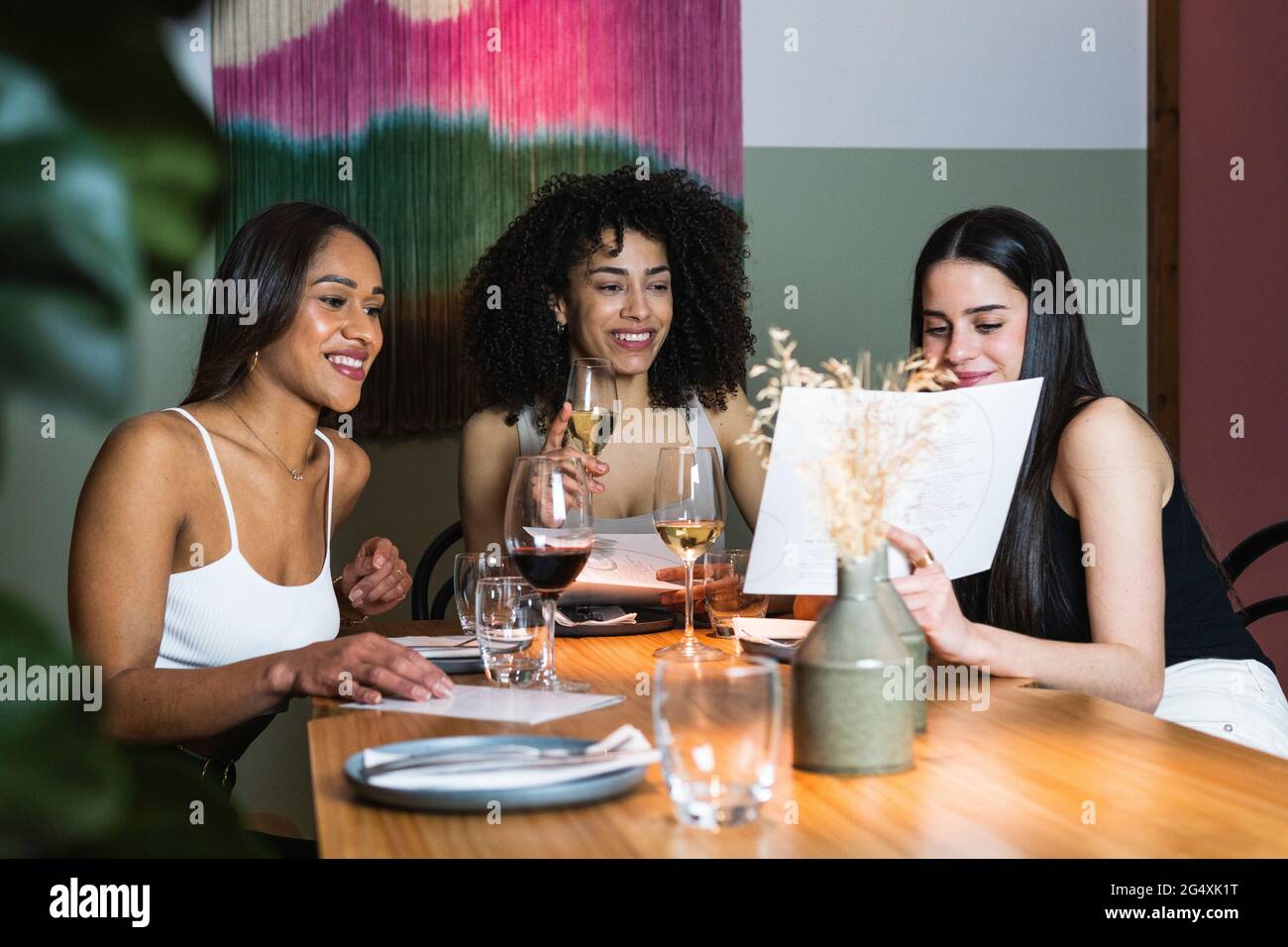 Woman showing menu to friends while having drink in restaurant Stock ...